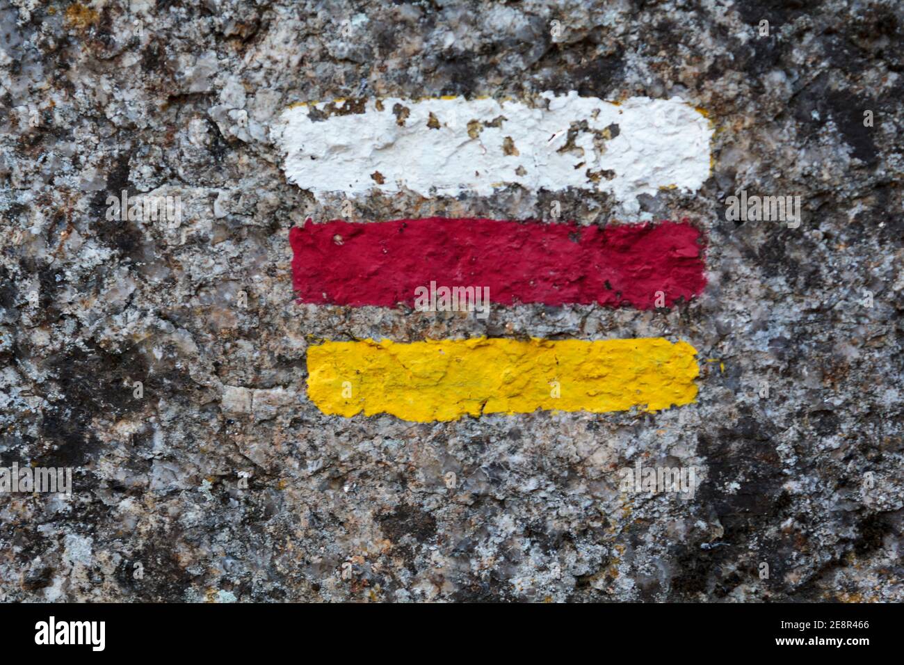 Trail marking sign with white, red and yellow stripes painted on wall ...