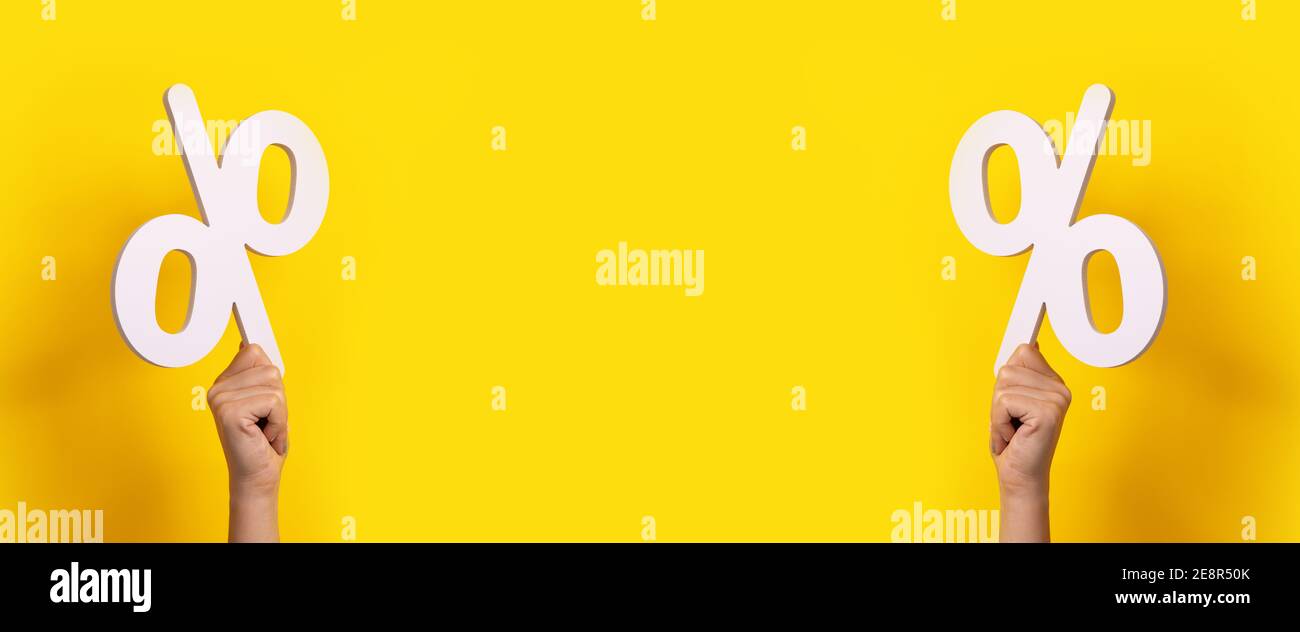 hands holding percentage sign over yellow background Stock Photo - Alamy