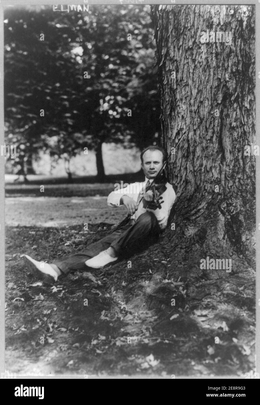 Mischa Elman, 1891-1967, sitting against tree, playing violin Stock ...