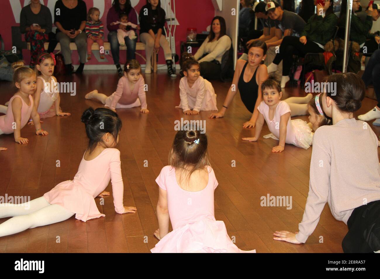 Girls practising ballet movements on the floor in a circle in class ...