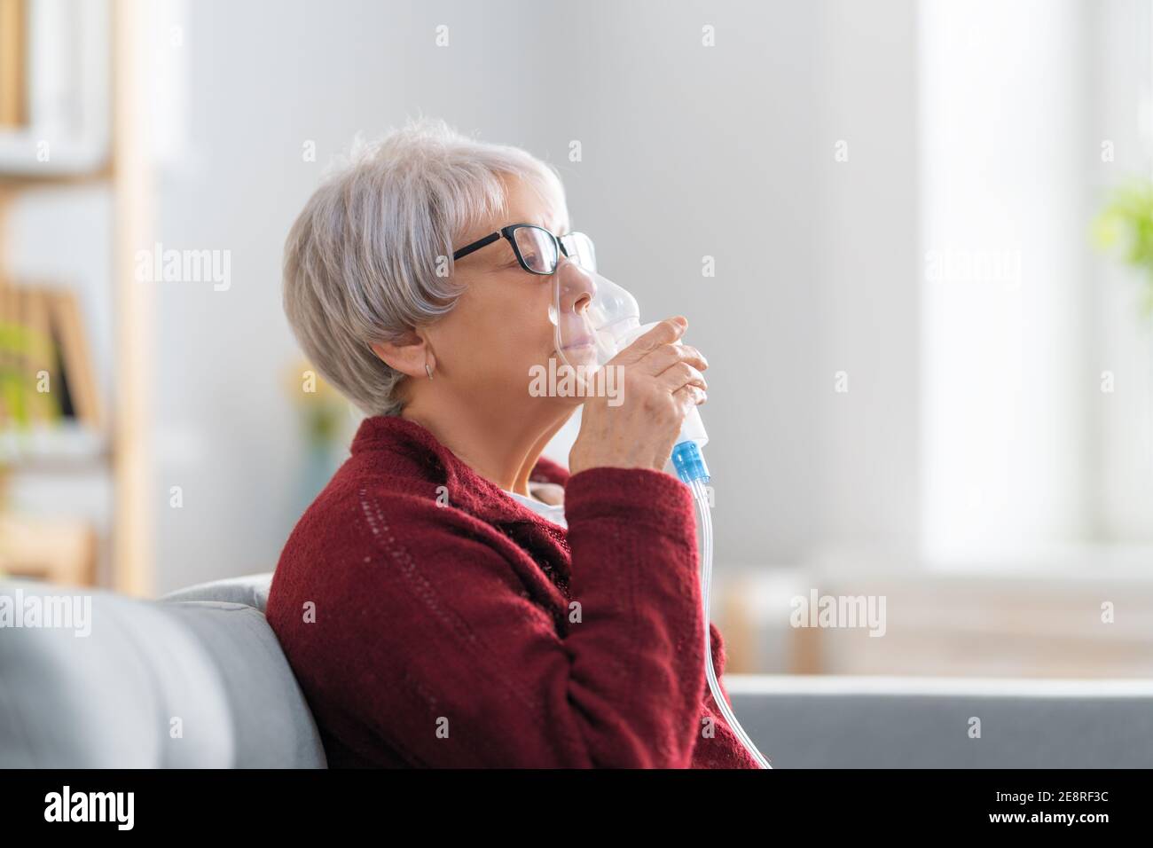 Elderly woman using inhaler for asthma and respiratory diseases at home ...
