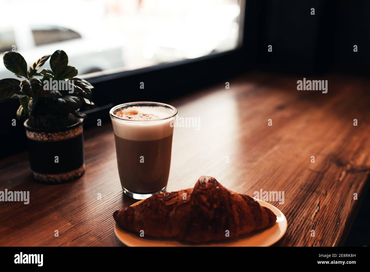 Cup of coffee, croissant at table near the window in cafe. Blurred ...