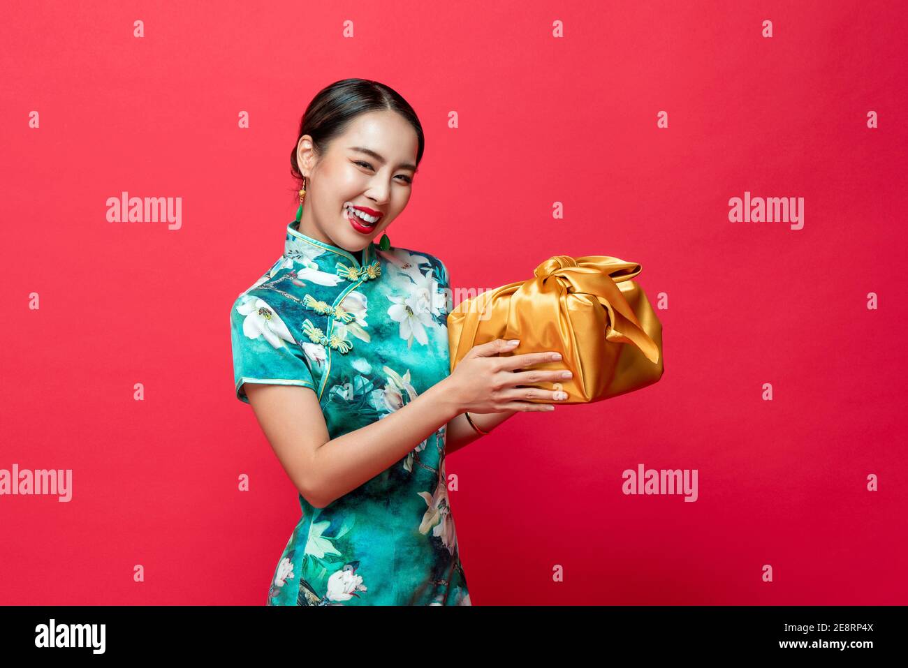 Happy smiling Asian woman in traditional costume holding gold gift box ...