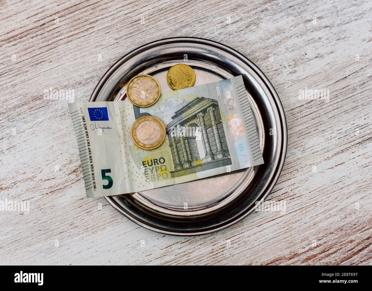 Overhead shot of five Euro banknote and dirty Euro coins on a silver ...