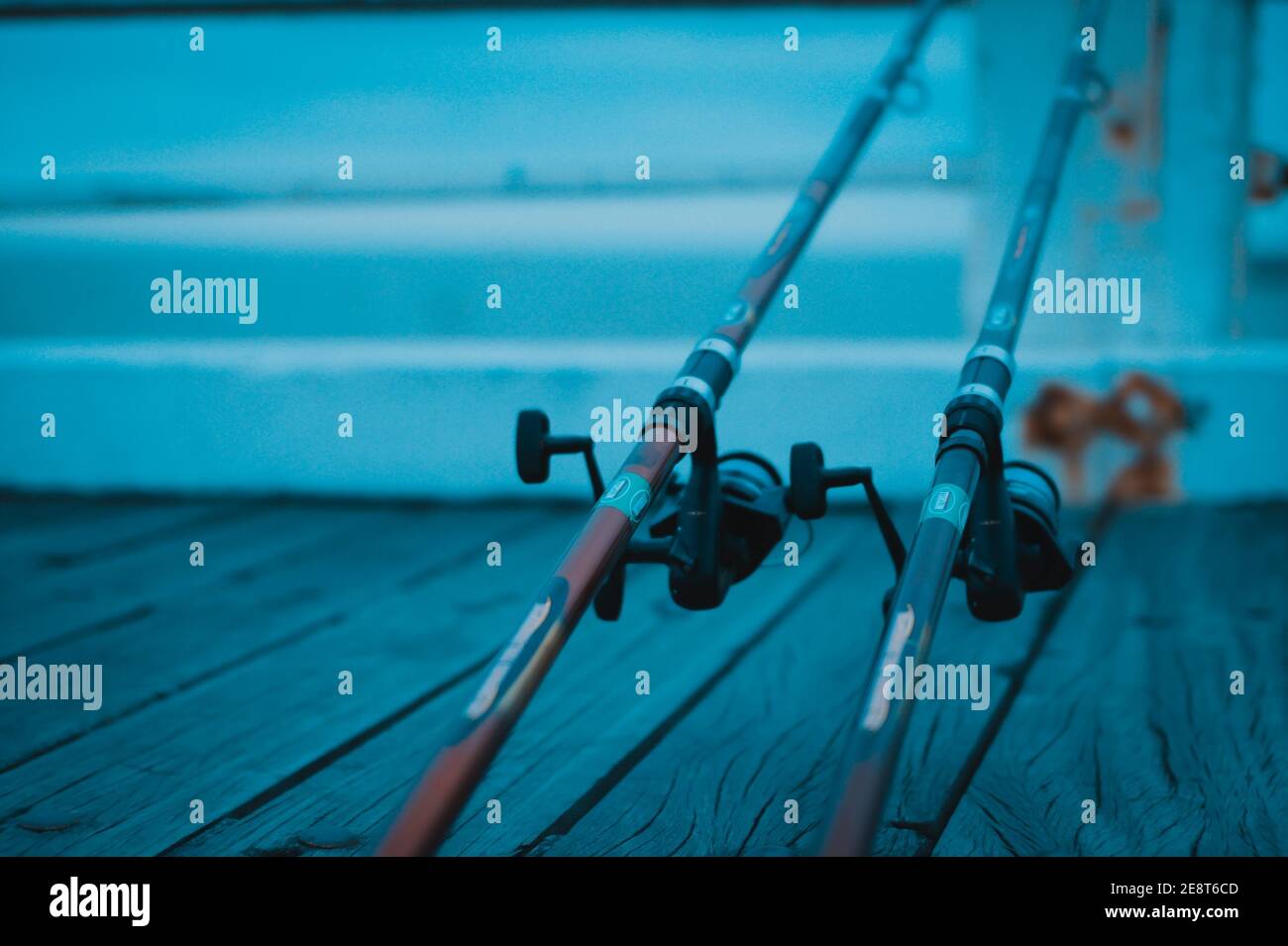 Closeup of dark-colored fishing rods on a wooden surface Stock Photo ...
