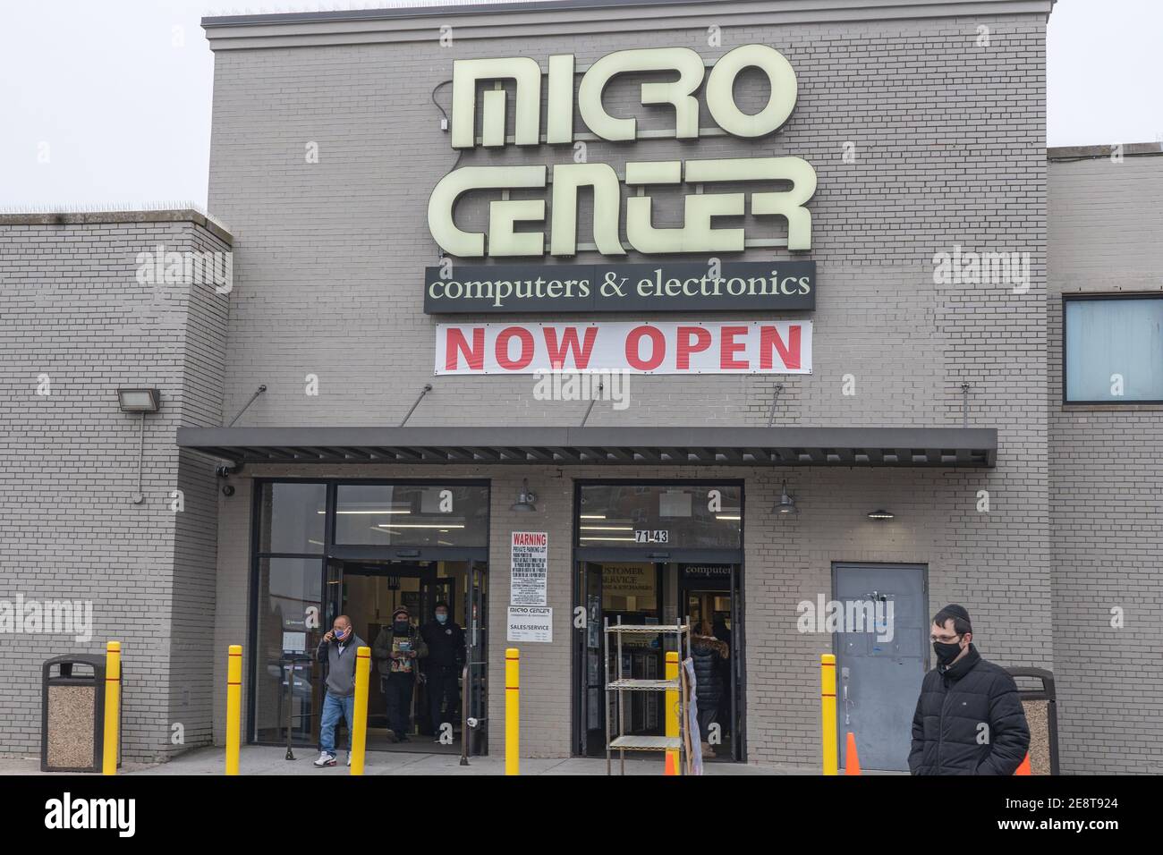 People wearing face masks exit a Micro Center store in Flushing, New ...