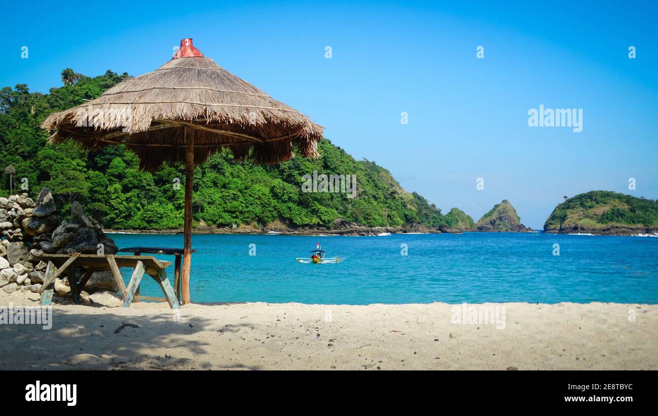 White sand on a beach in Indonesia. Umbrella and boat Stock Photo - Alamy