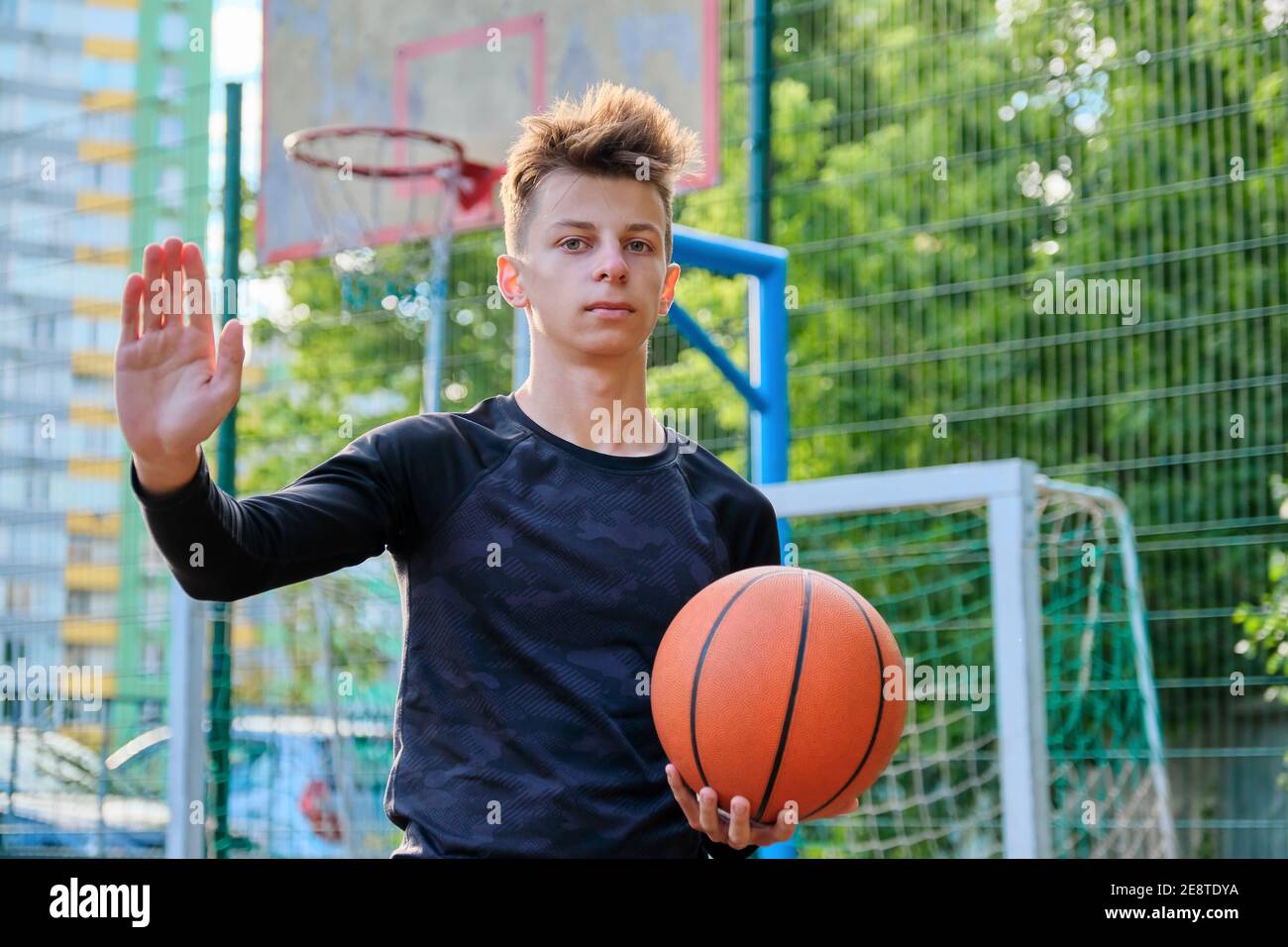 Serious guy teenager with basketball ball showing stop sign hand ...