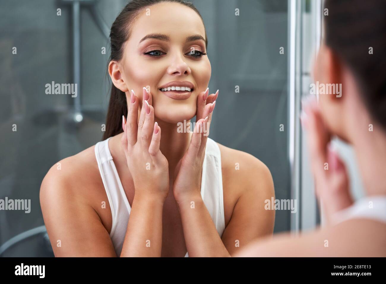 Woman looking on reflection in the mirror after shower Stock Photo - Alamy