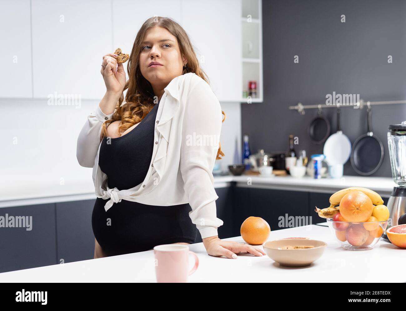 Lost battle eating cookie overweight girl standing at kitchen. Dieting ...