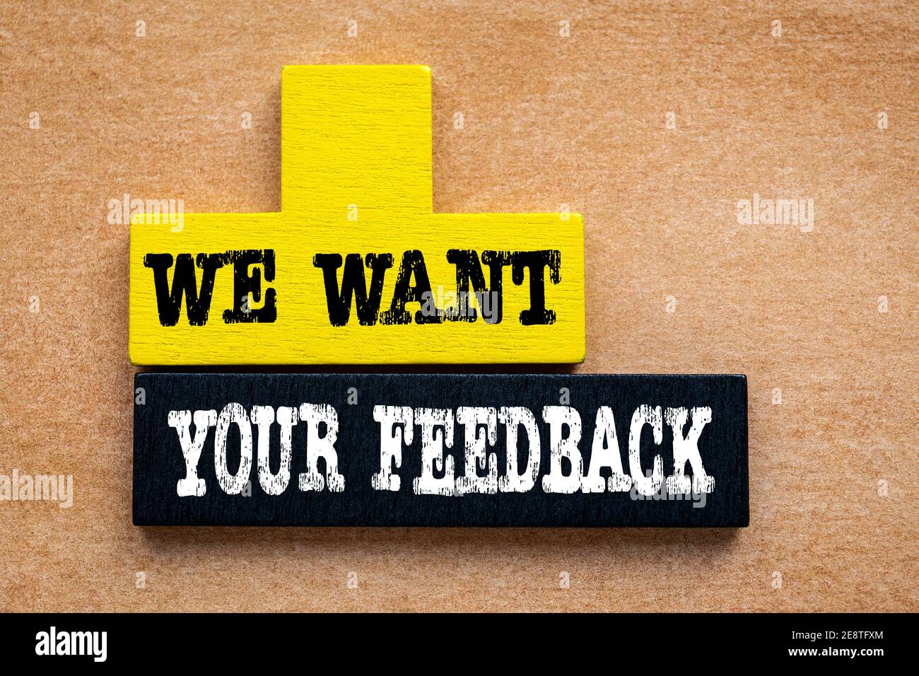 WE WANT YOUR FEEDBACK . Yellow and black wooden block on an orange ...