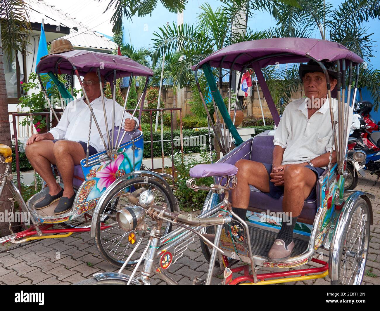 Two middle-aged men who drive rickshaws, sitting in the rickshaw ...