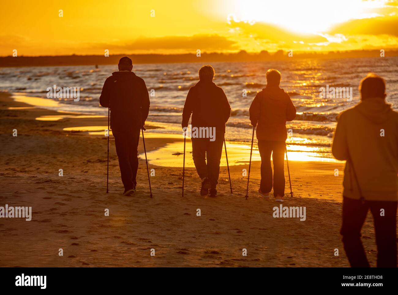 Active and healthy lifestyle. Nordic walking on a sandy beach sea shore ...