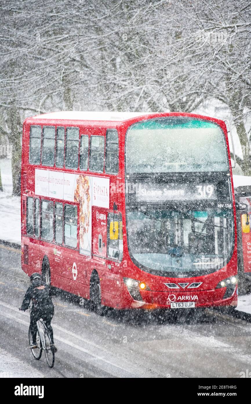 A cyclist and a 319 bus in heavy snow in London Stock Photo - Alamy