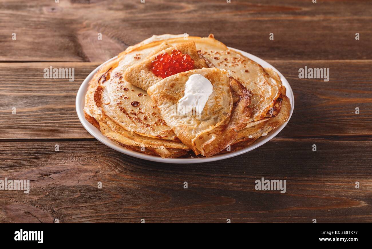 Traditional Russian Crepes Blini stacked in a plate with red caviar ...