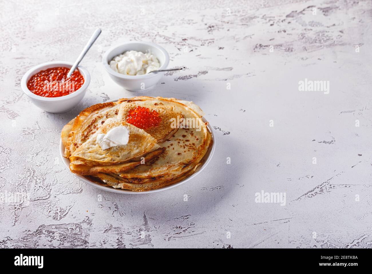 Traditional Russian Crepes Blini stacked in a plate with red caviar ...