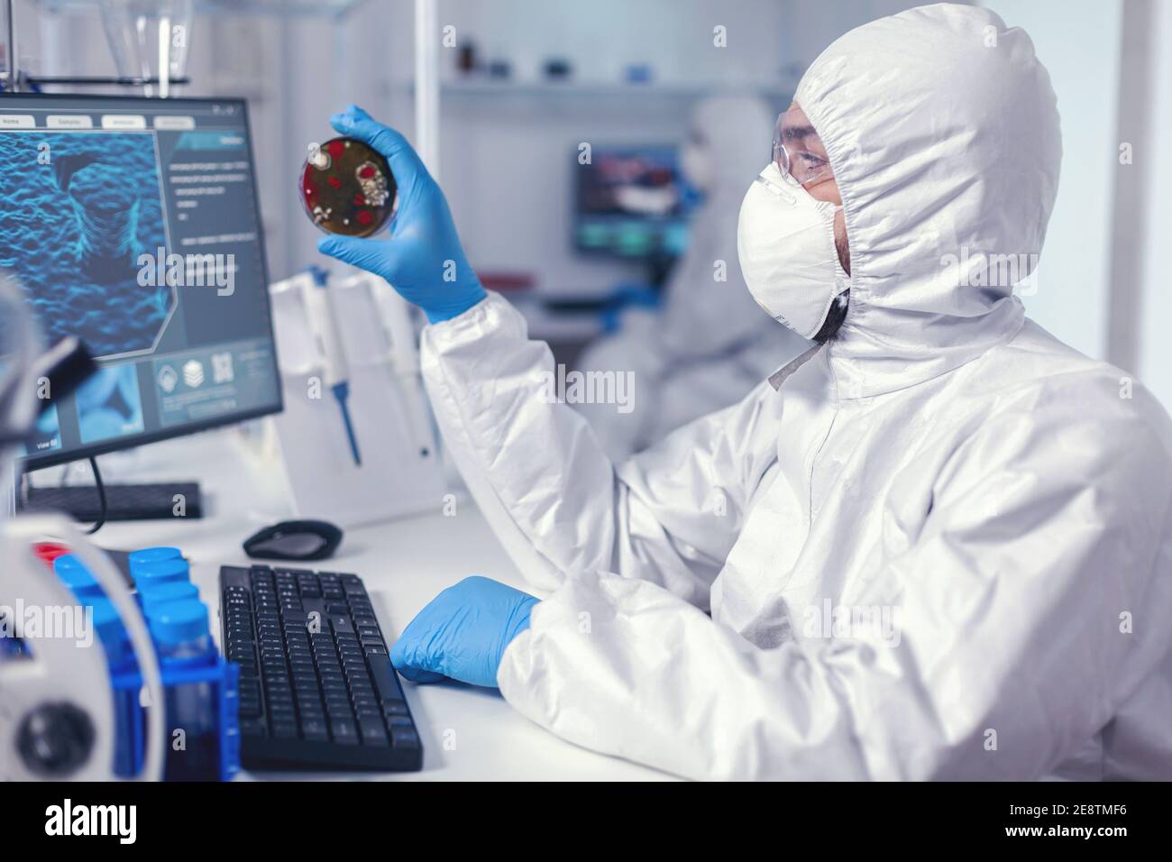 Medicine researcher works on sars-cov-2 on petri dish dressed in ...