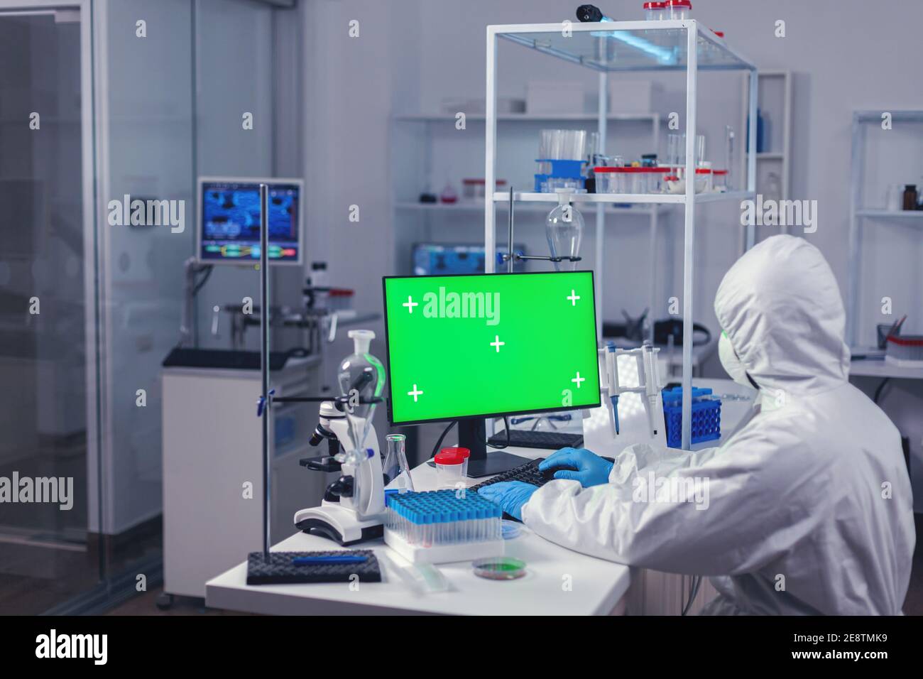 Medical researcher typing on keyboard of computer with green screen ...