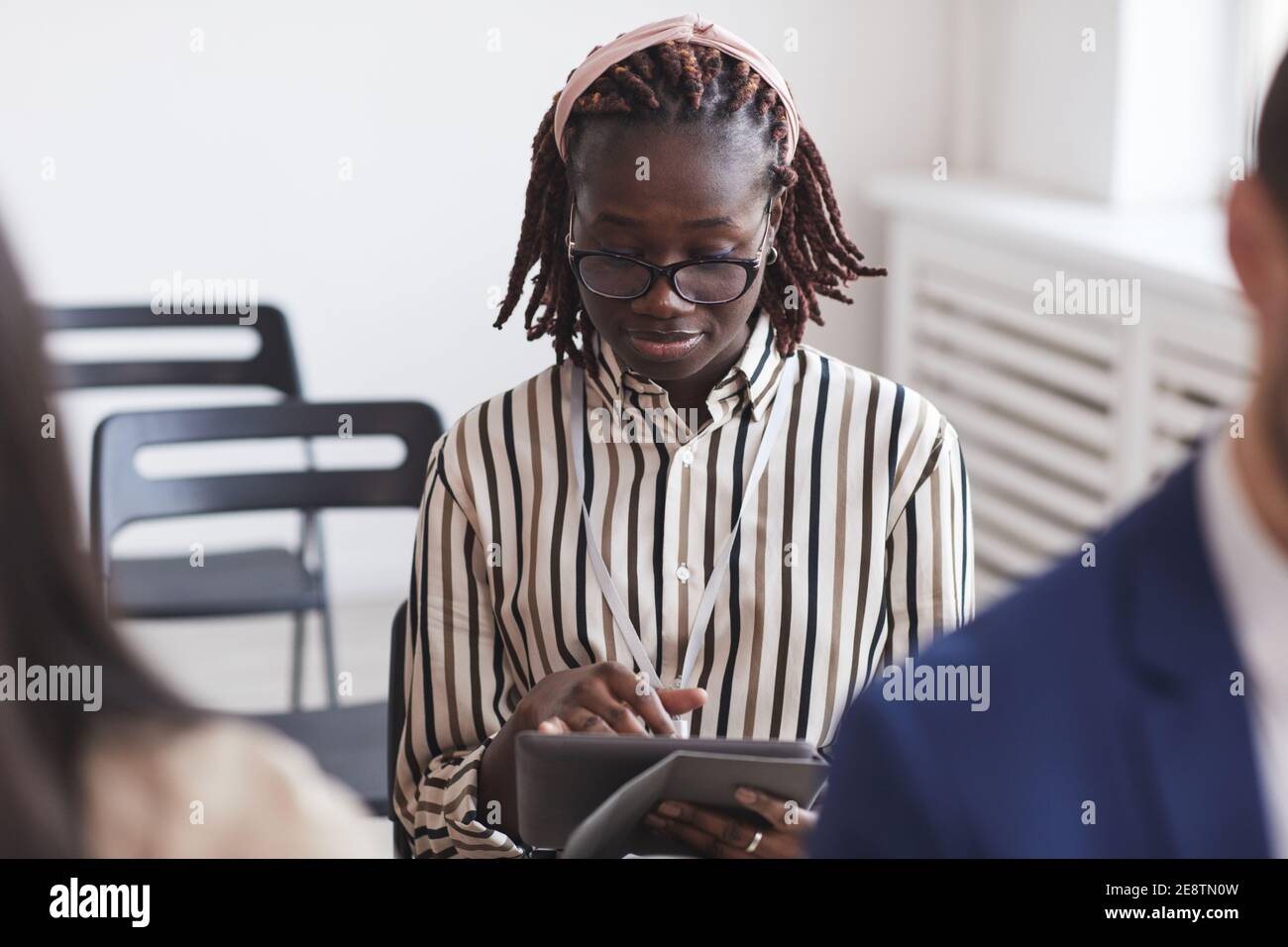 Portrait of young African-American woman taking notes on digital tablet ...