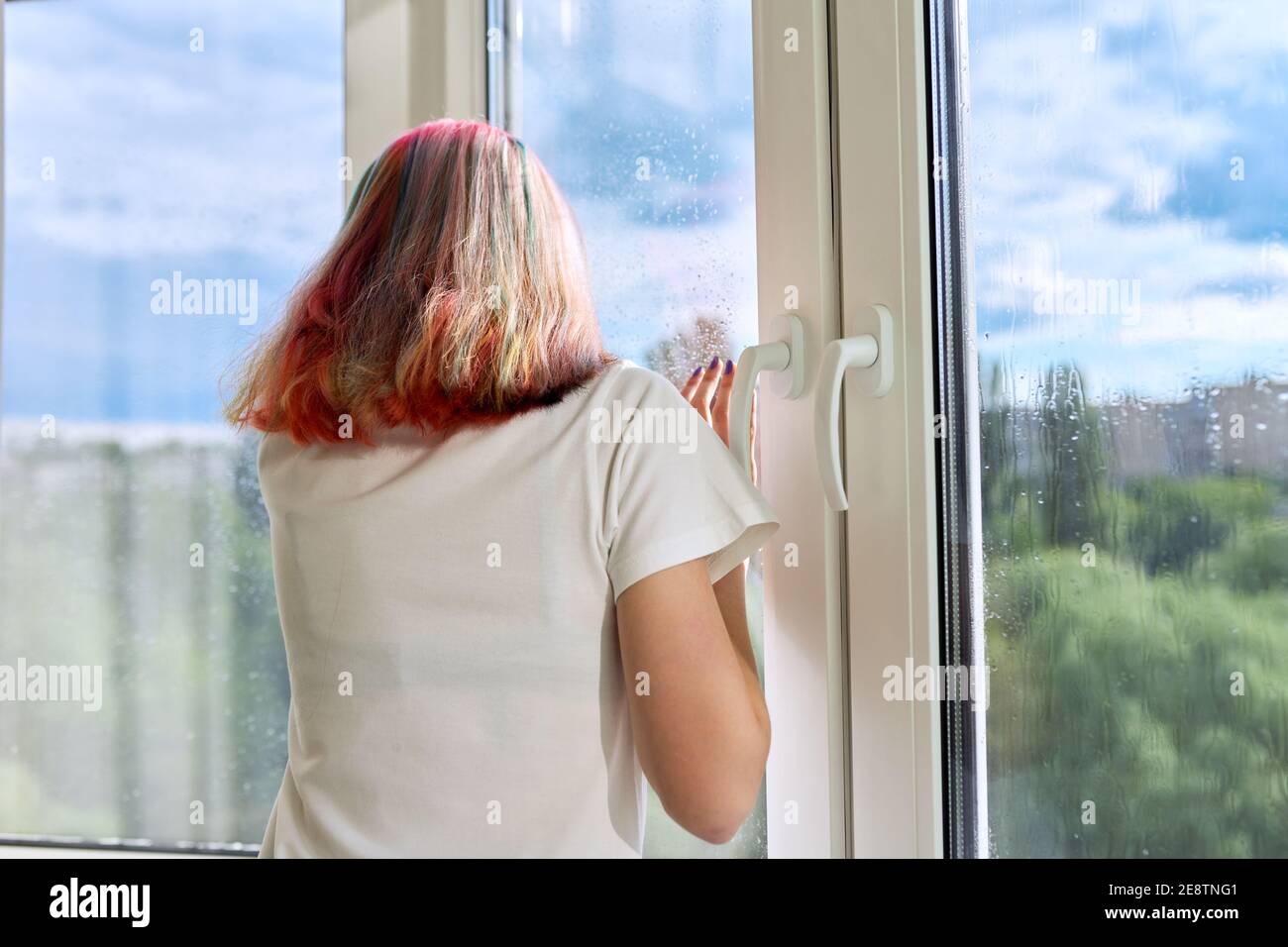 Back view of young woman looking out rainy summer window Stock Photo ...
