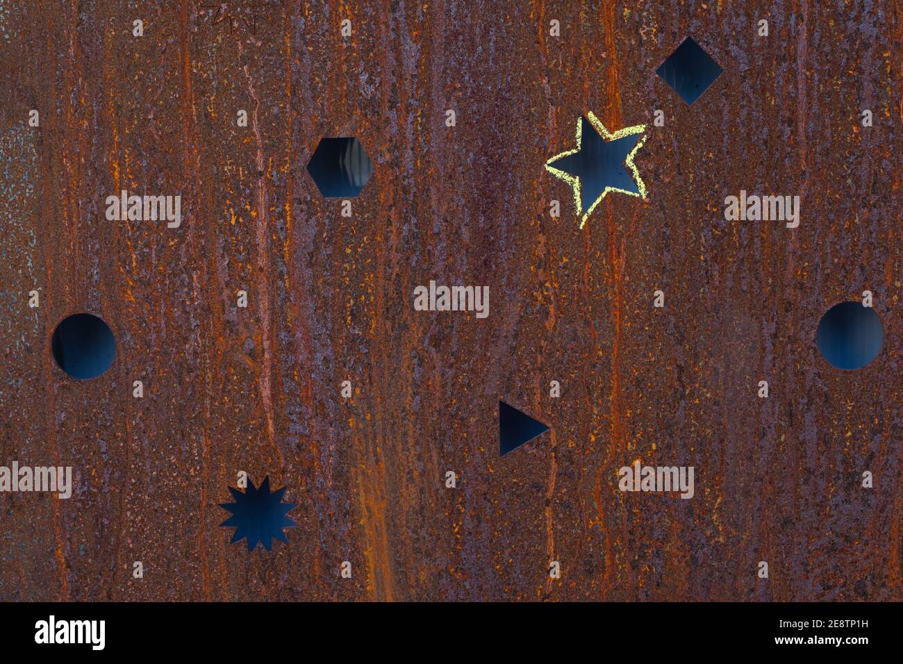Old rusty metal sheet with cuts in the shape of a circle and a star and ...