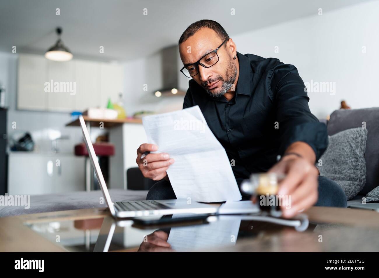 Mixed race man accounting at home Stock Photo - Alamy