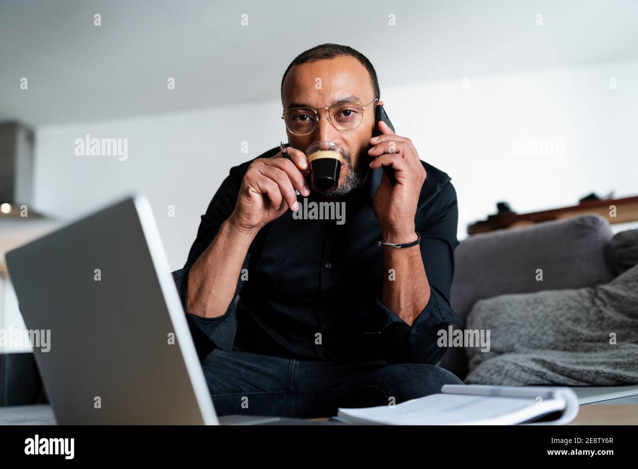 Serious man drinking coffee while managing accounts at home Stock Photo ...