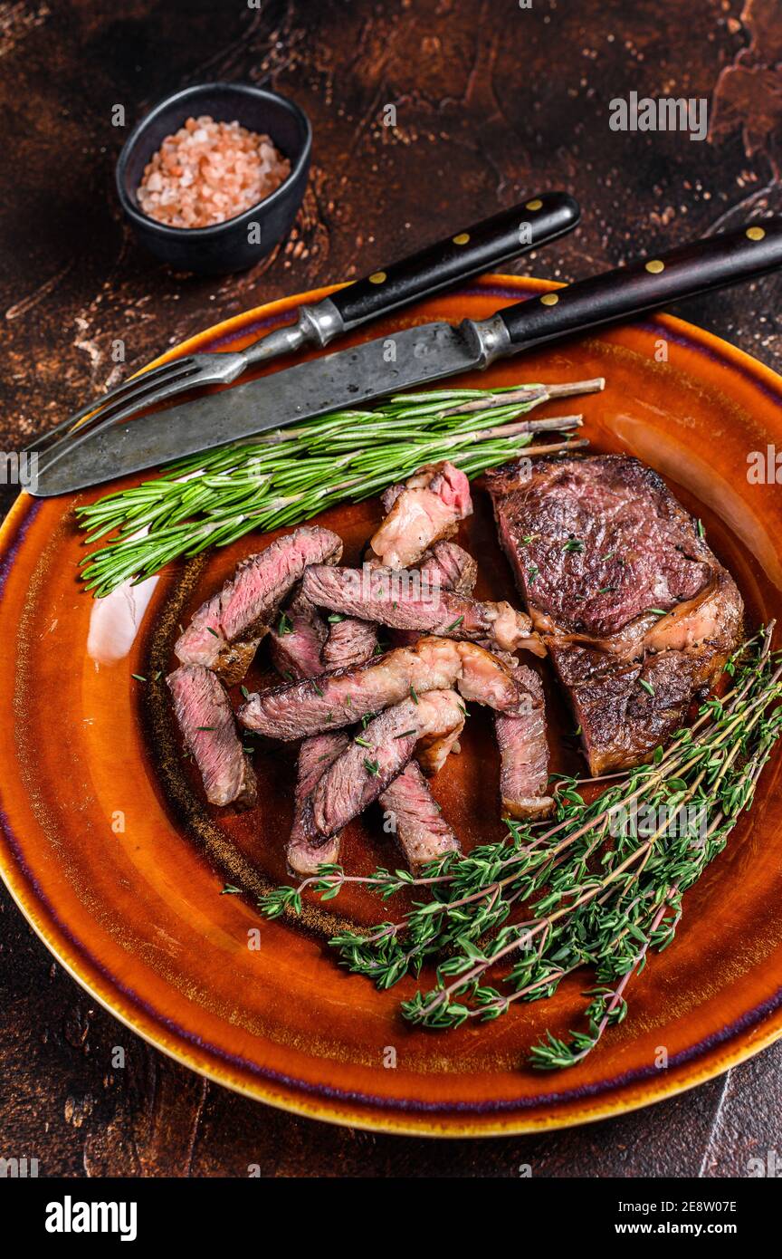 Grilled sliced rib eye or ribeye beef meat steak on a rustic plate ...