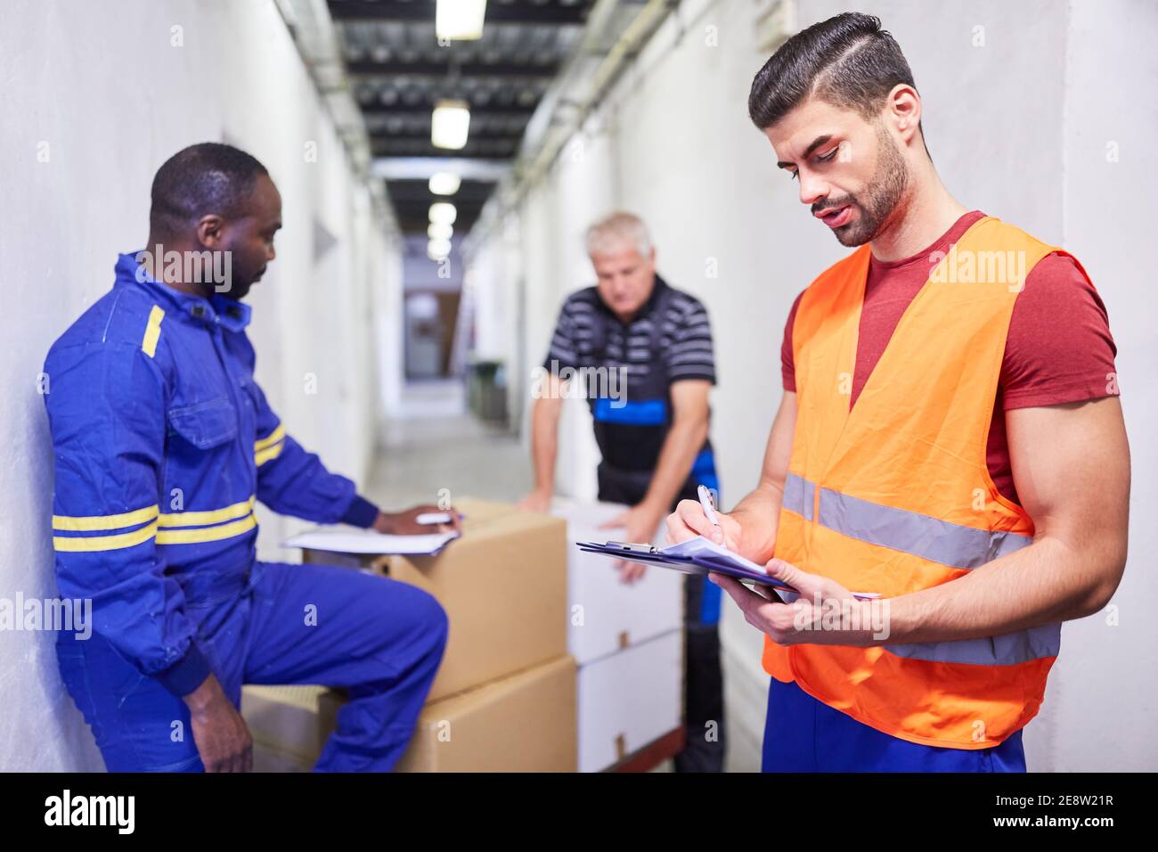 Warehouse clerk with checklist on clipboard checks delivery of goods at ...