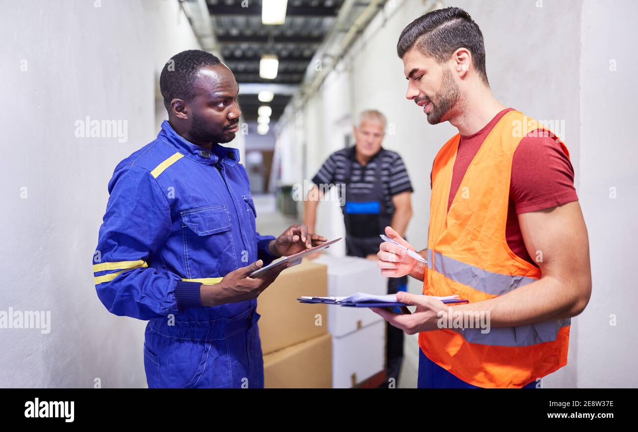 Warehouse clerk and a colleague check delivery of goods with checklist ...