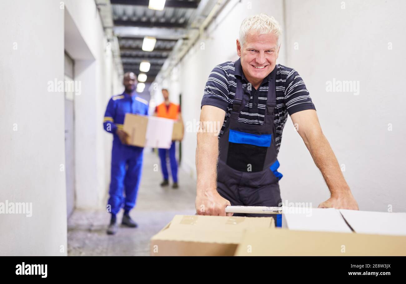 Smiling worker pushes packages on a push cart to the incoming goods ...