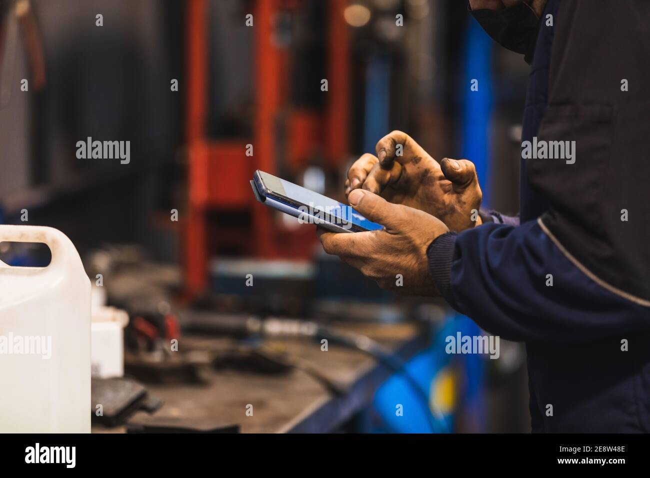 Mechanic using cell phone in the workshop. Hands full of grease ...