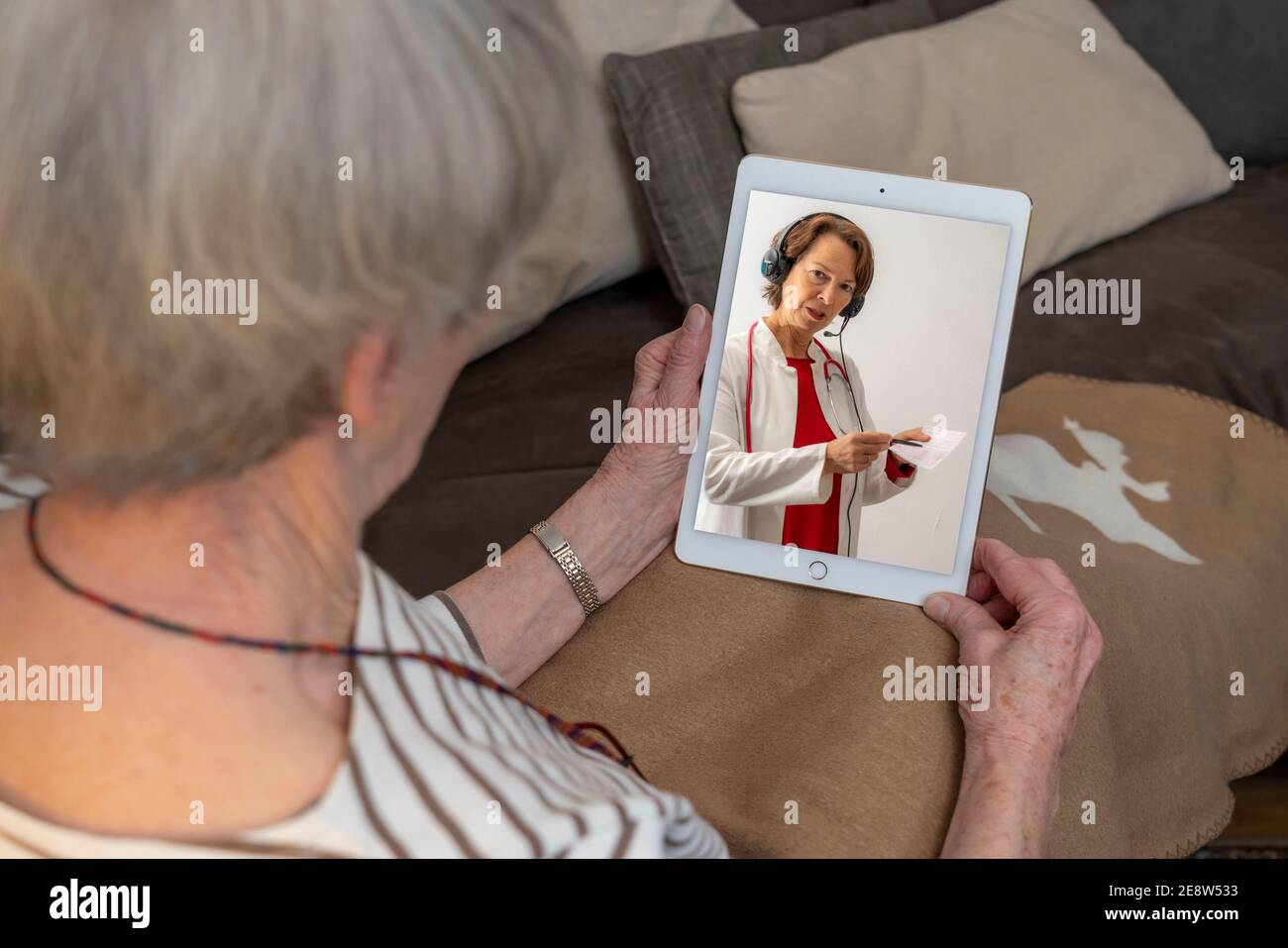 Symbolic image of telemedicine, elderly patient talks to a doctor in a ...