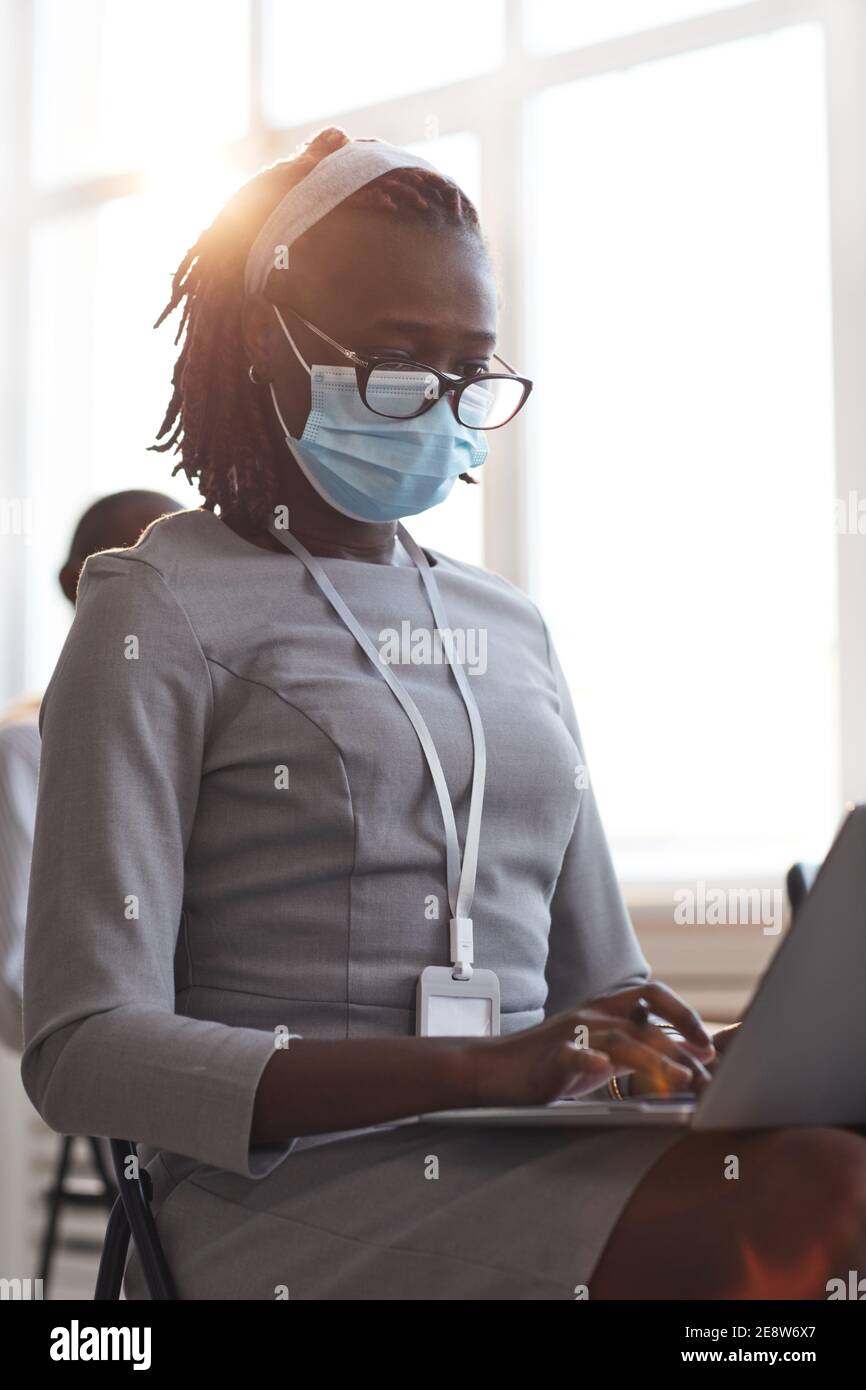 Vertical portrait of young African-American businesswoman wearing mask ...