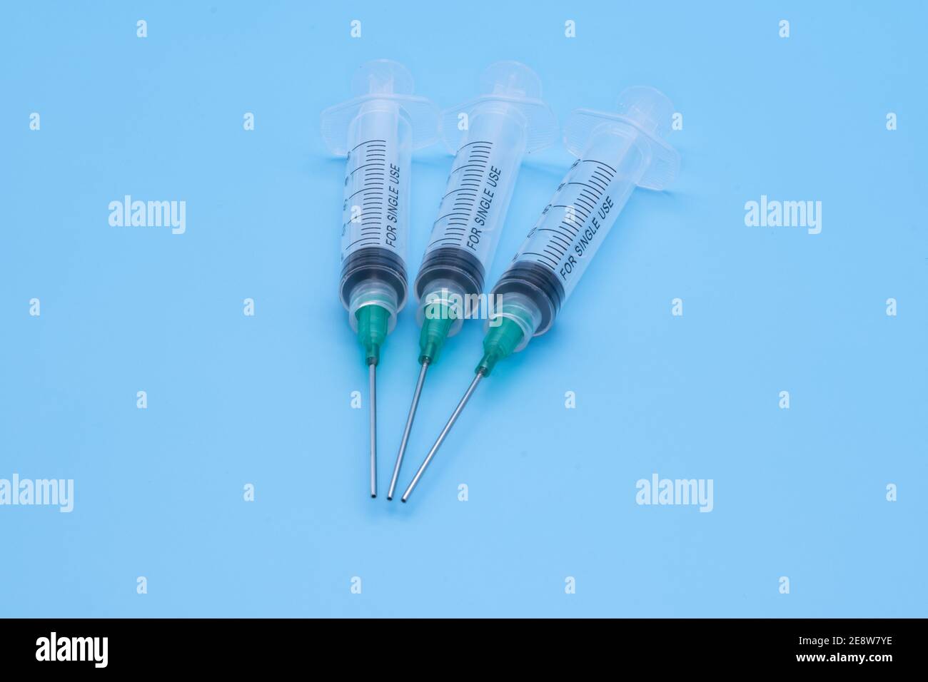 clear plastic syringes with needles isolated against a light blue ...