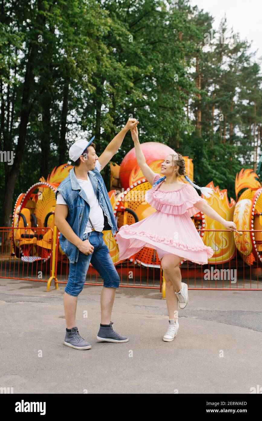Happy young couple in love having fun in an amusement park and dancing ...