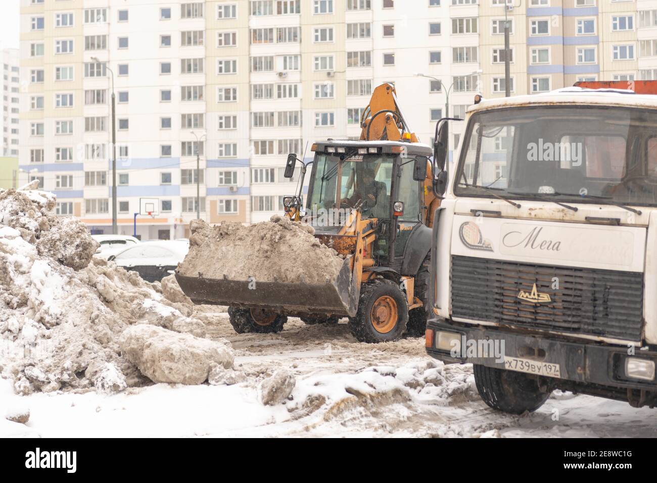 Moscow. Russia. Winter 2021. A large tractor loads the car with snow in ...