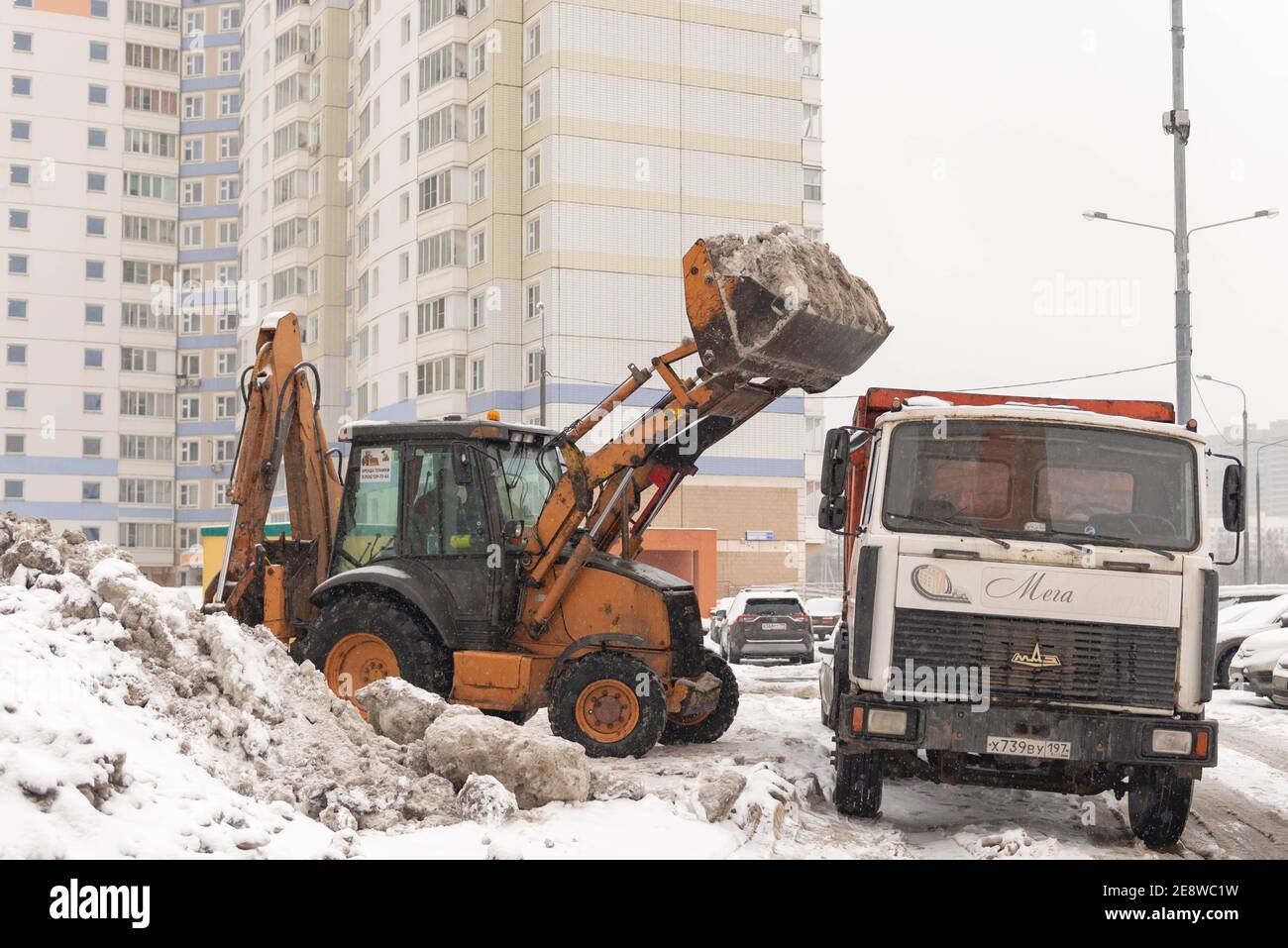 Moscow. Russia. Winter 2021. A large tractor loads the car with snow in ...