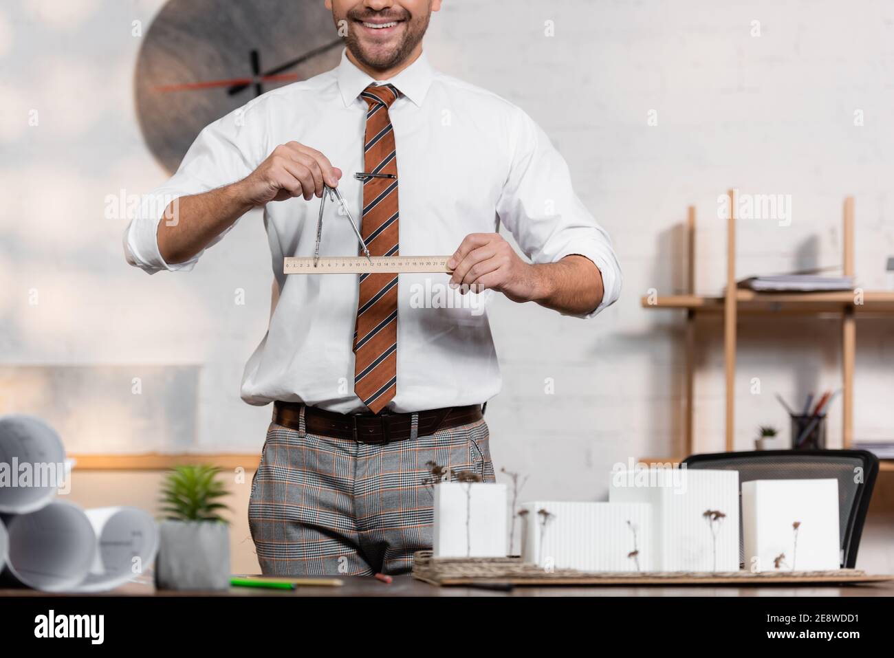 cropped view of smiling architect with ruler and divider near ...