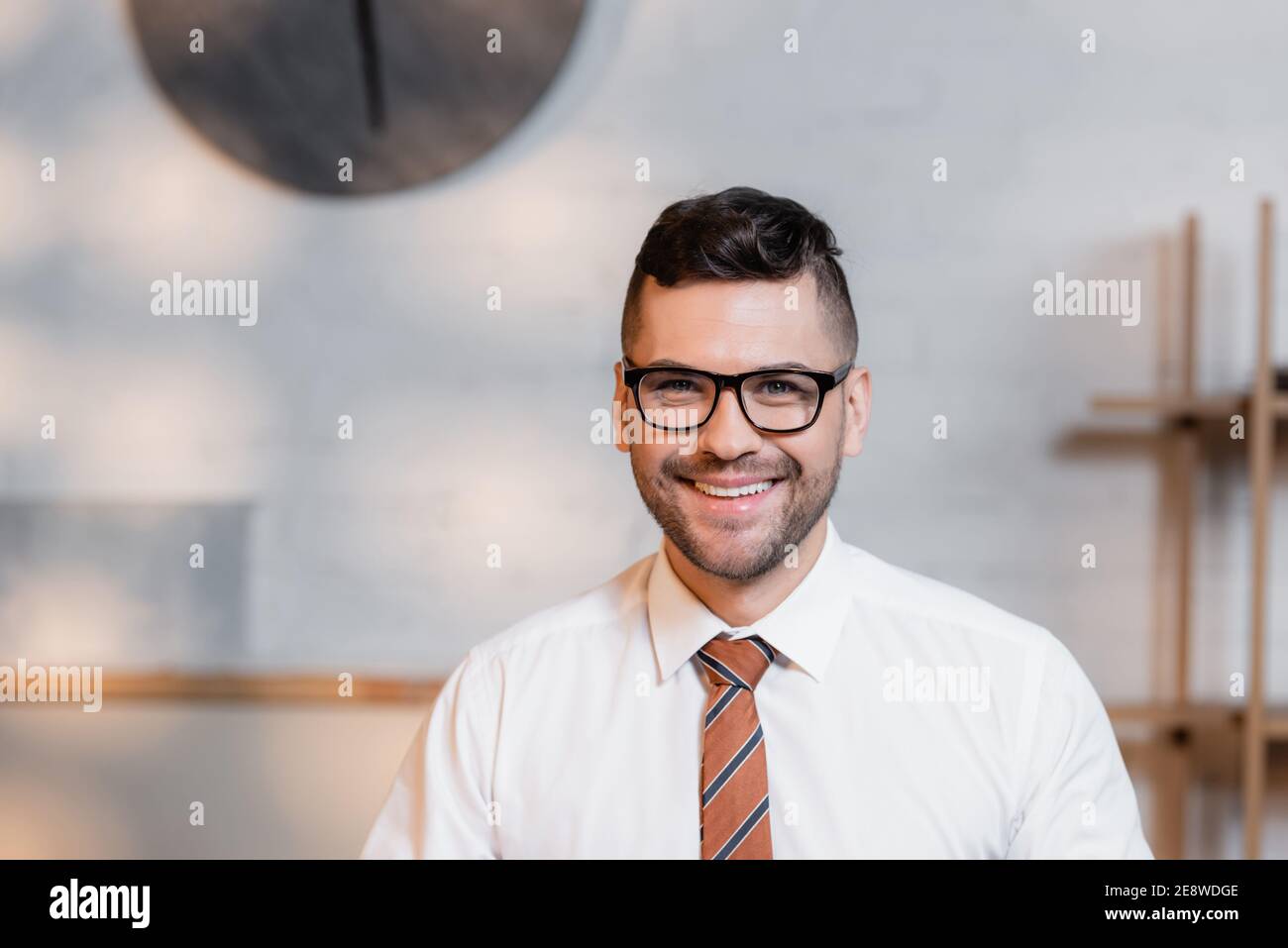 happy architect in eyeglasses smiling at camera in architectural agency ...