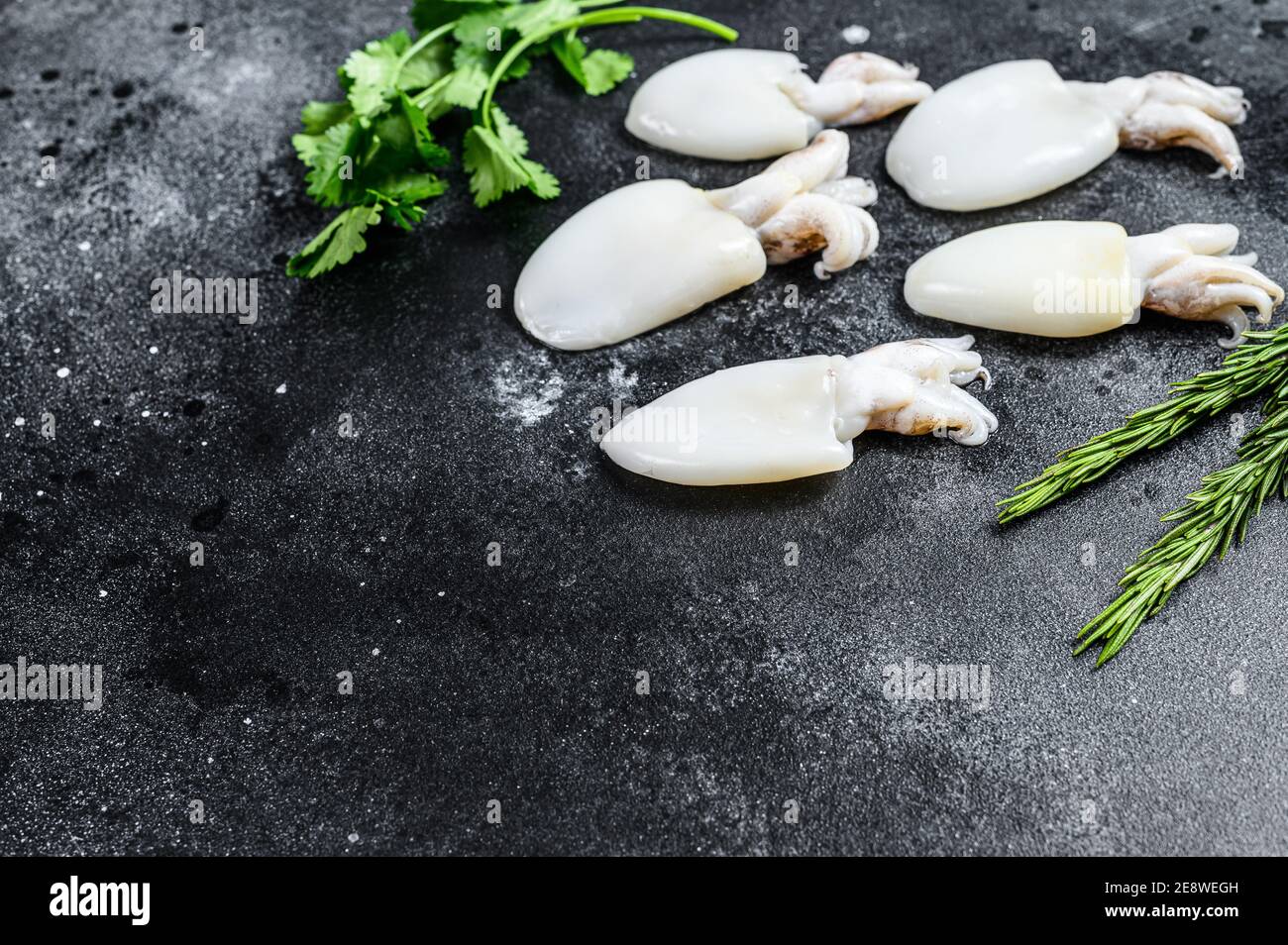 Fresh raw cuttlefish with rosemary and parsley. Black background. Top ...