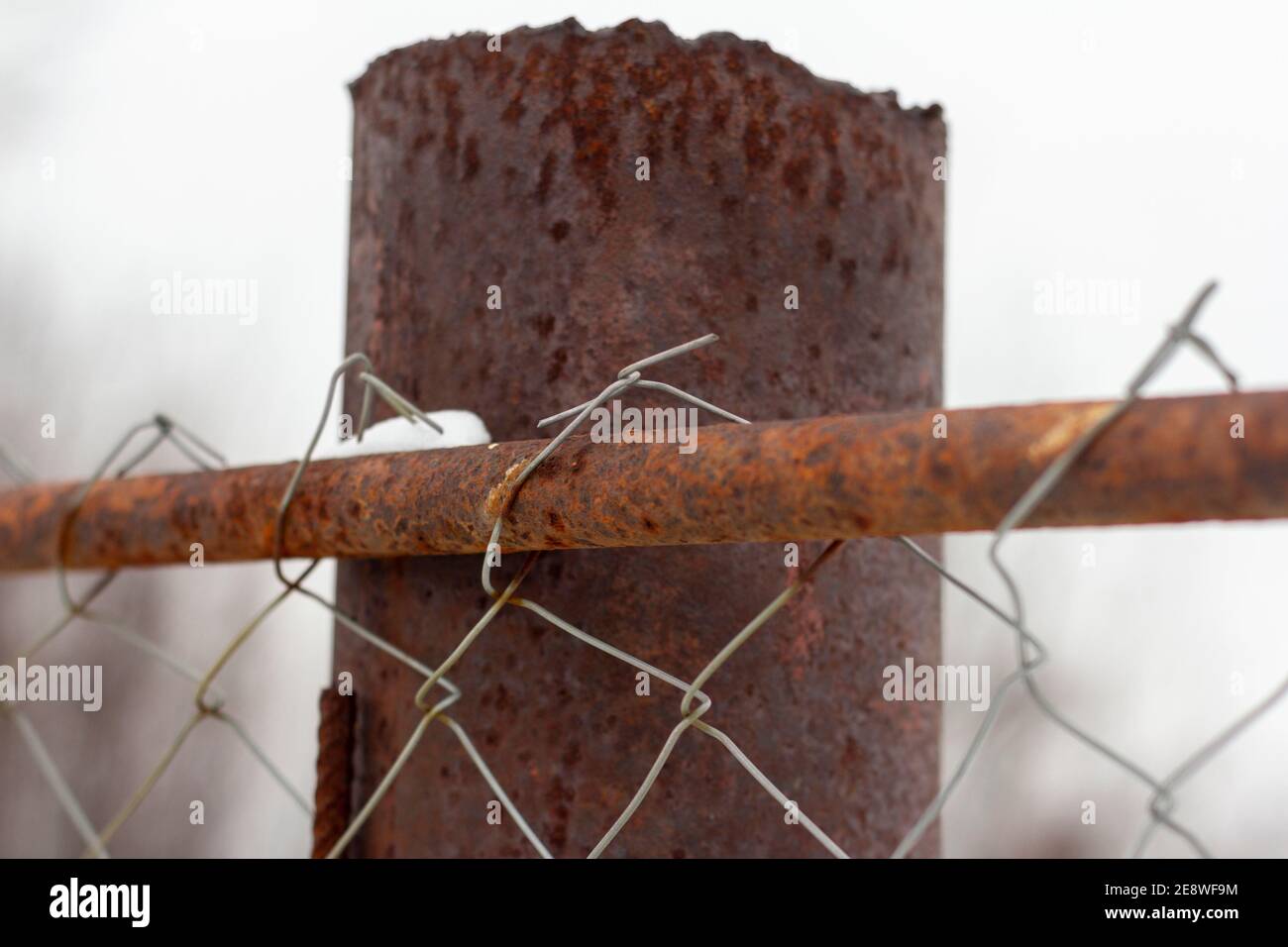 Close-up on a rusty metal pole rusty steel mesh chain link.An old fence ...