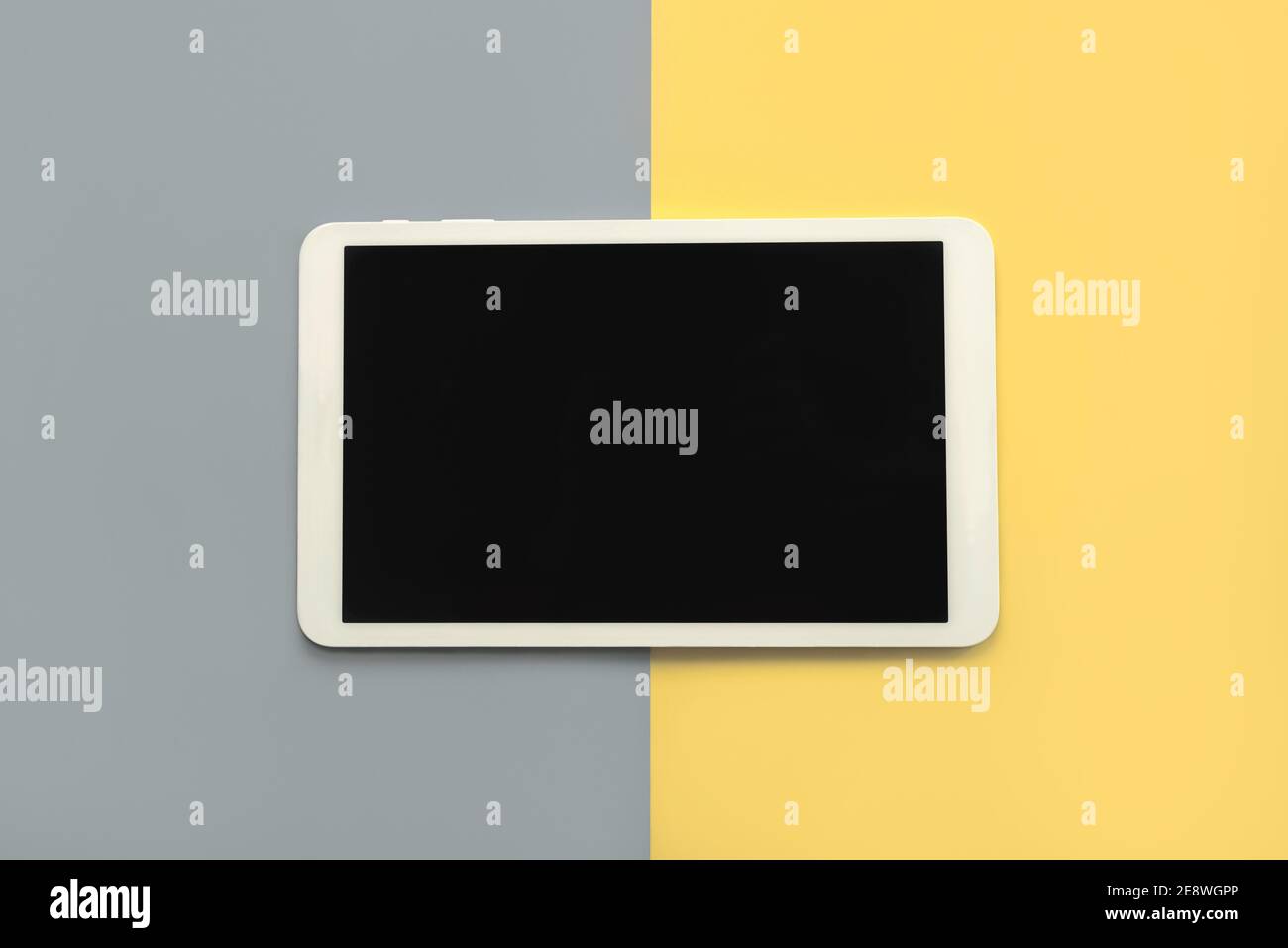 White digital tablet with black screen on yellow and gray background ...