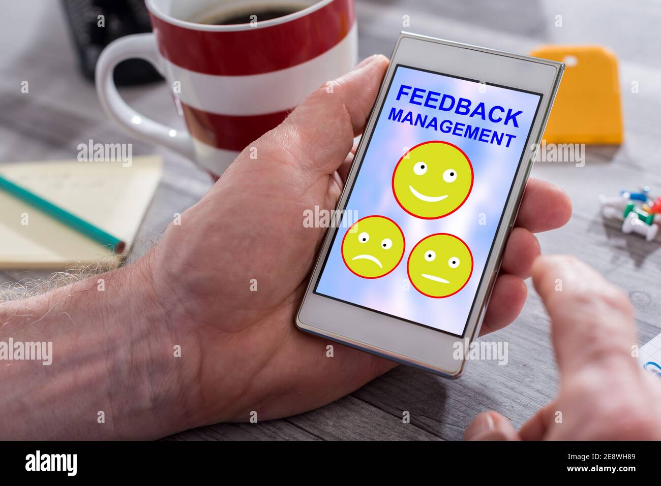 Male hand holding a smartphone with feedback management concept Stock ...