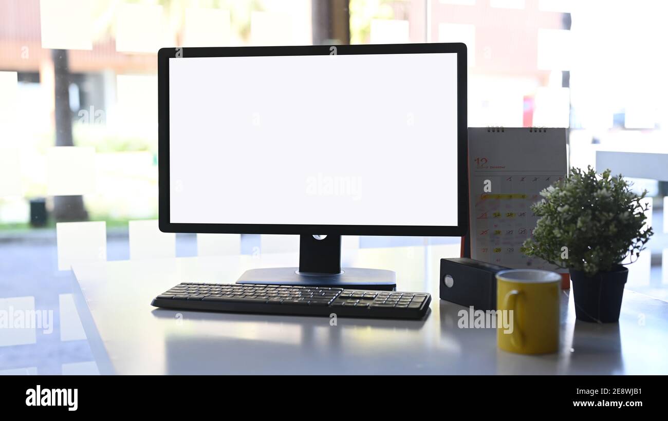 Front view computer with white screen, coffeecup, plant and calendar on ...