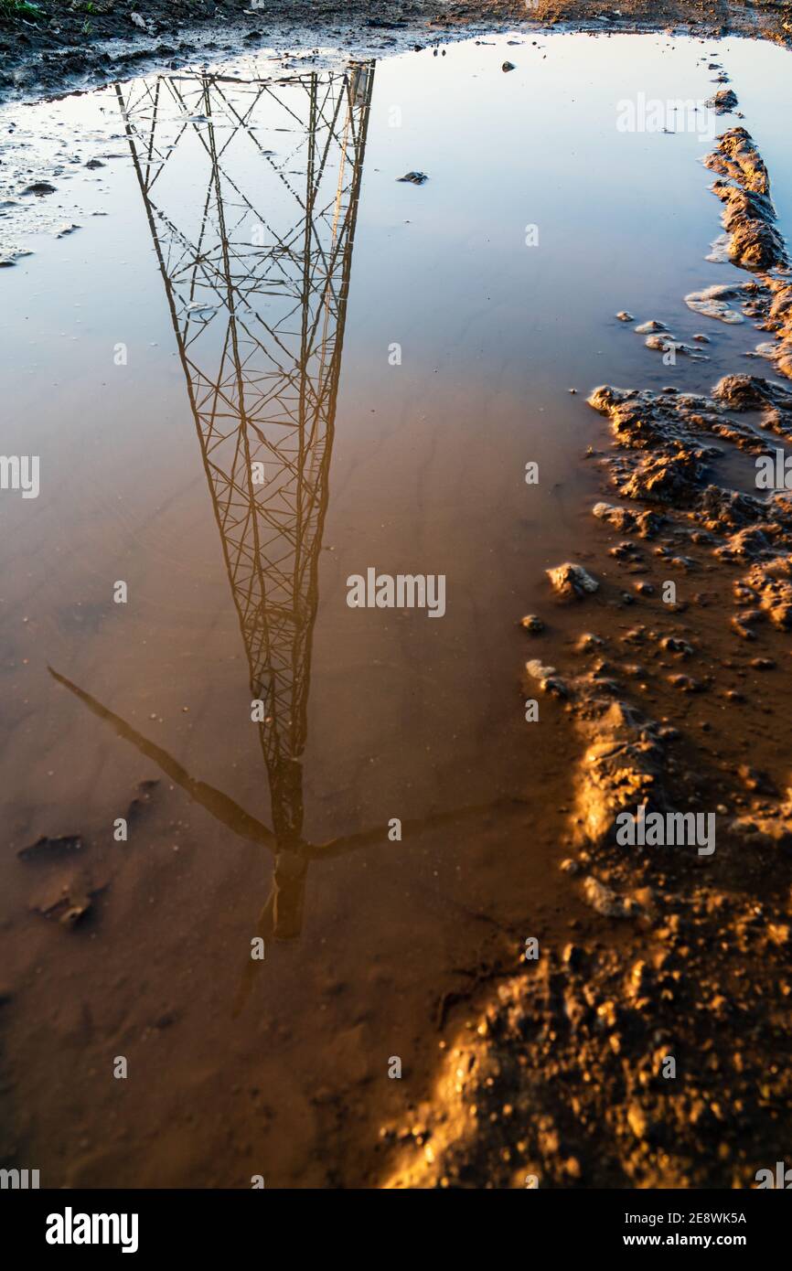 Wind turbine in the reflection of a dirty puddle. Theme of renewable ...