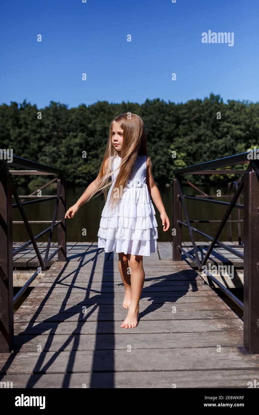 Portrait of a little girl outdoors in the summer by the lake. Little ...