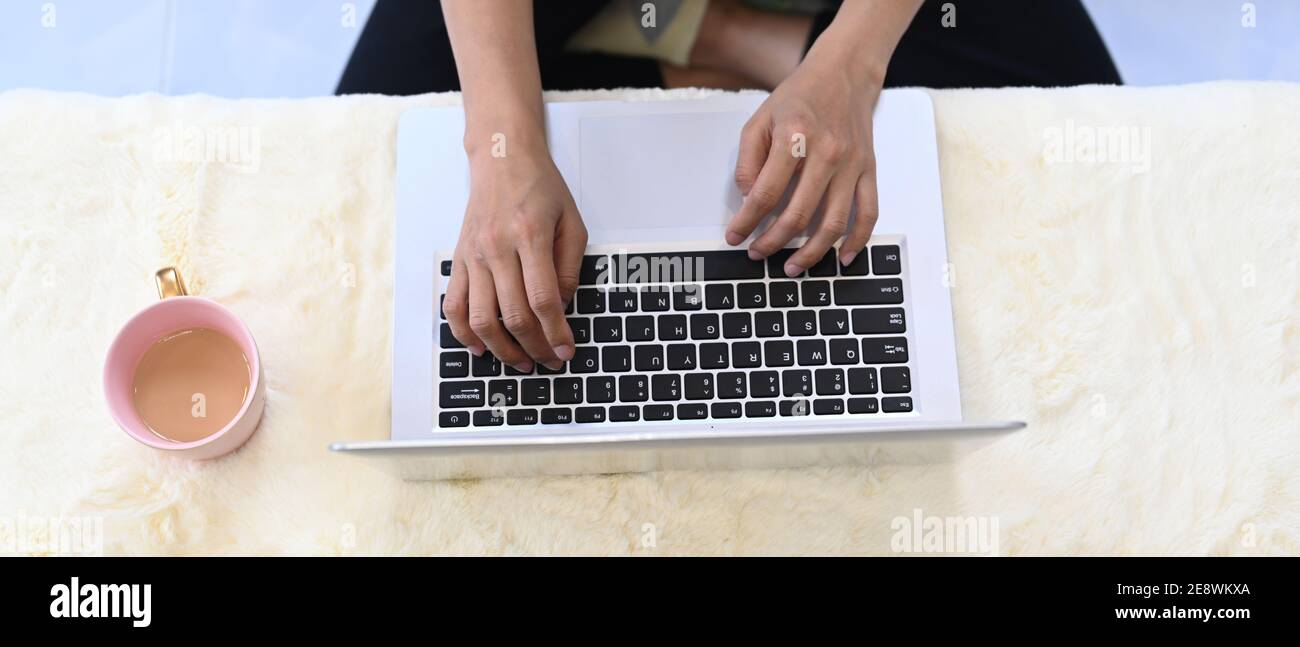 Overhead shot of young woman hands typing on keyboard of laptop ...