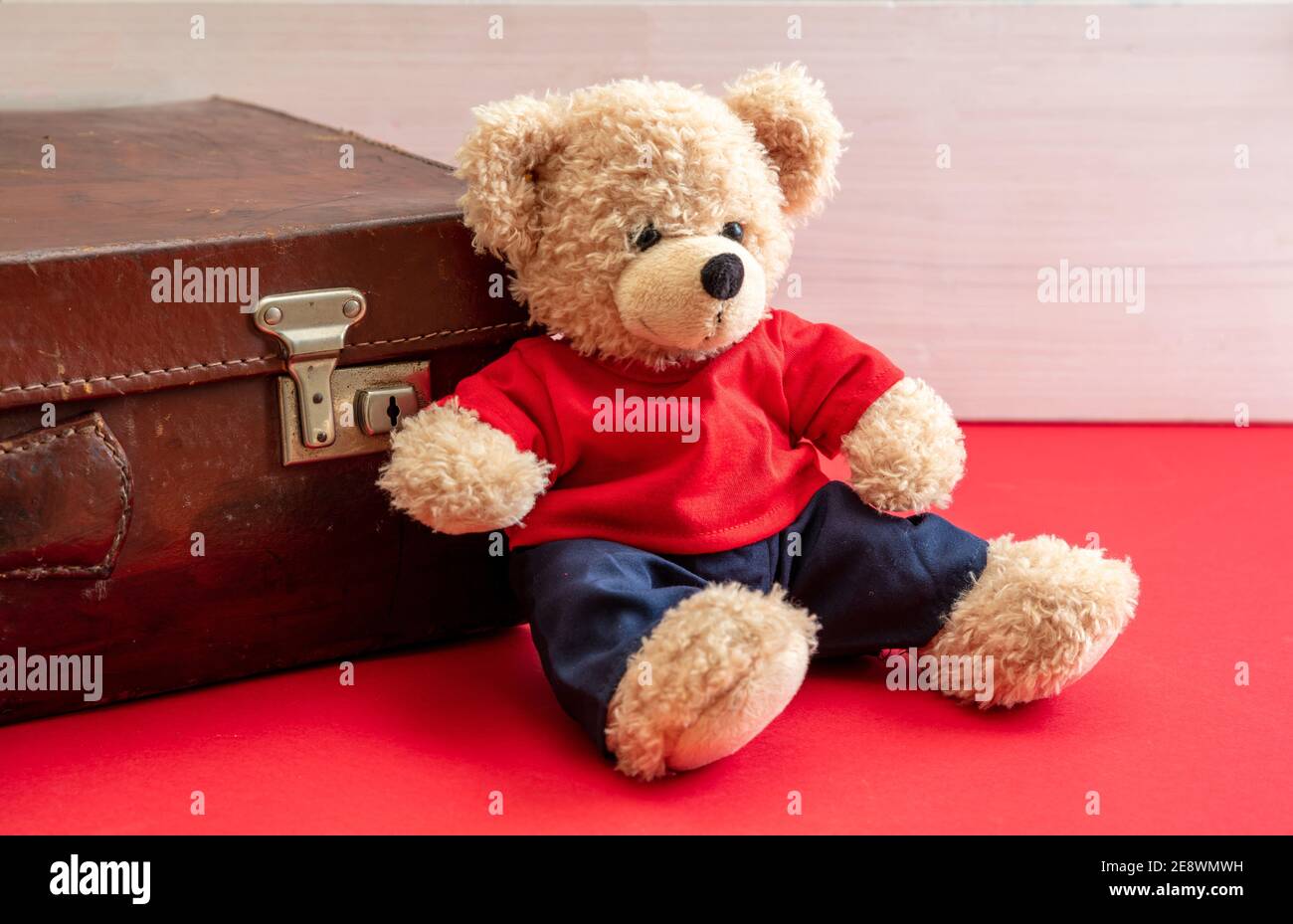 Travel suitcase and cute teddy sitting on red floor. Kid abandoned ...