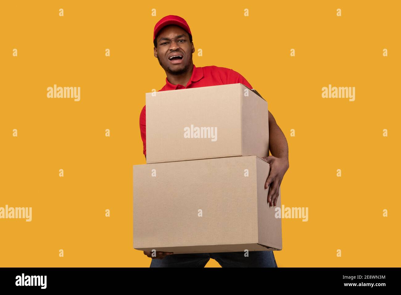 Black delivery man holding pile of heavy boxes Stock Photo - Alamy